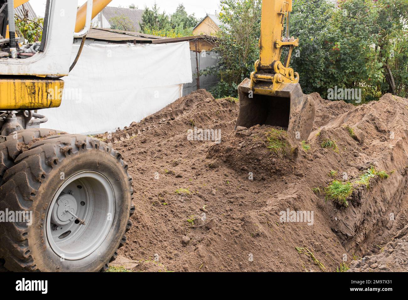 An excavator bucket digs the ground in an industrial area. Excavation ...