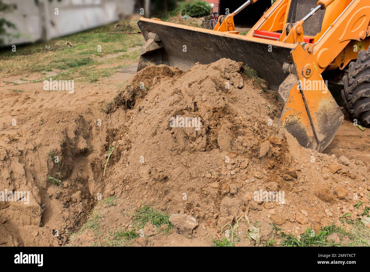 Excavator or bulldozer bucket flattens the ground or road in the ...