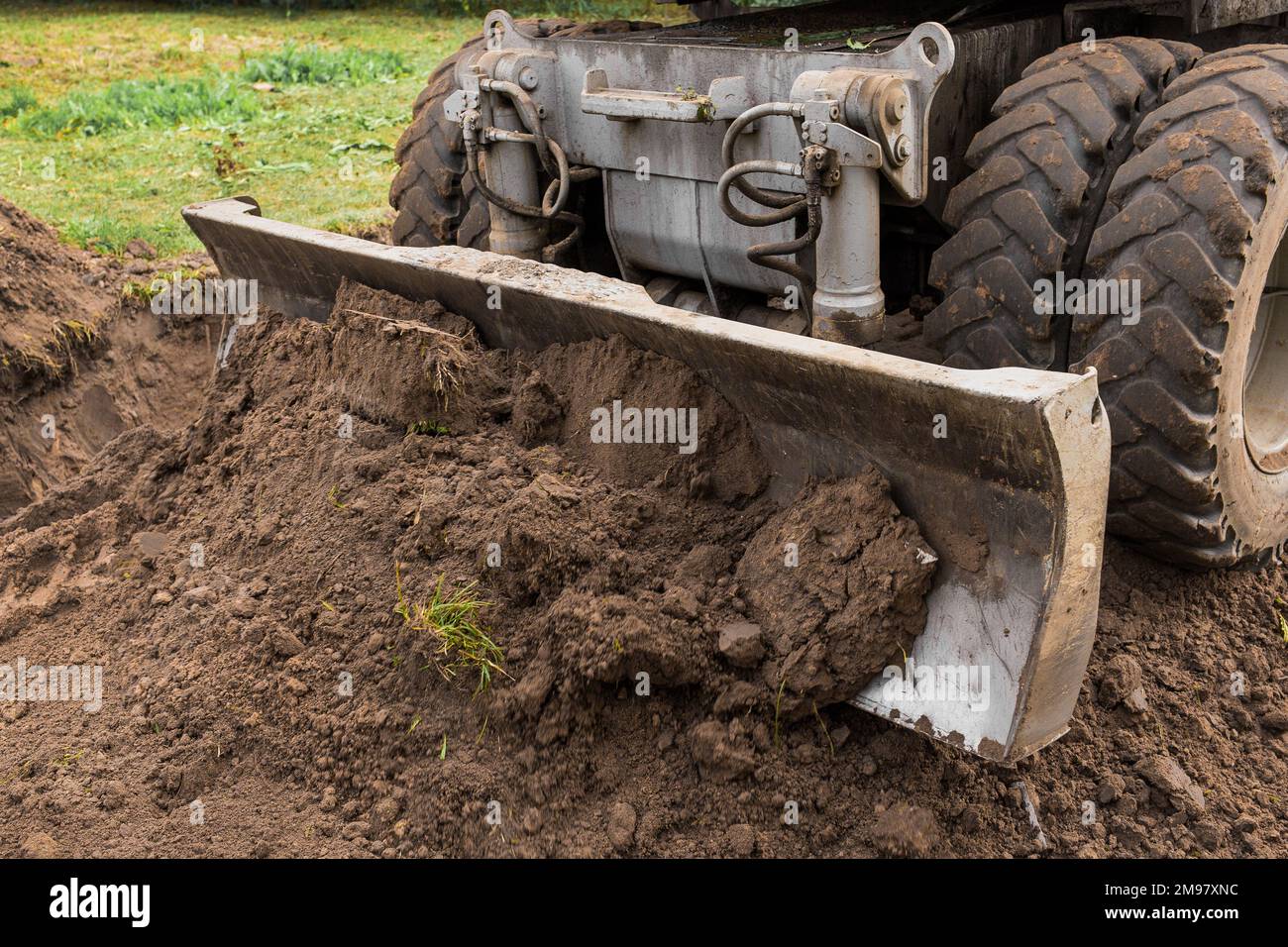 Excavator or bulldozer bucket flattens the ground or road in the ...