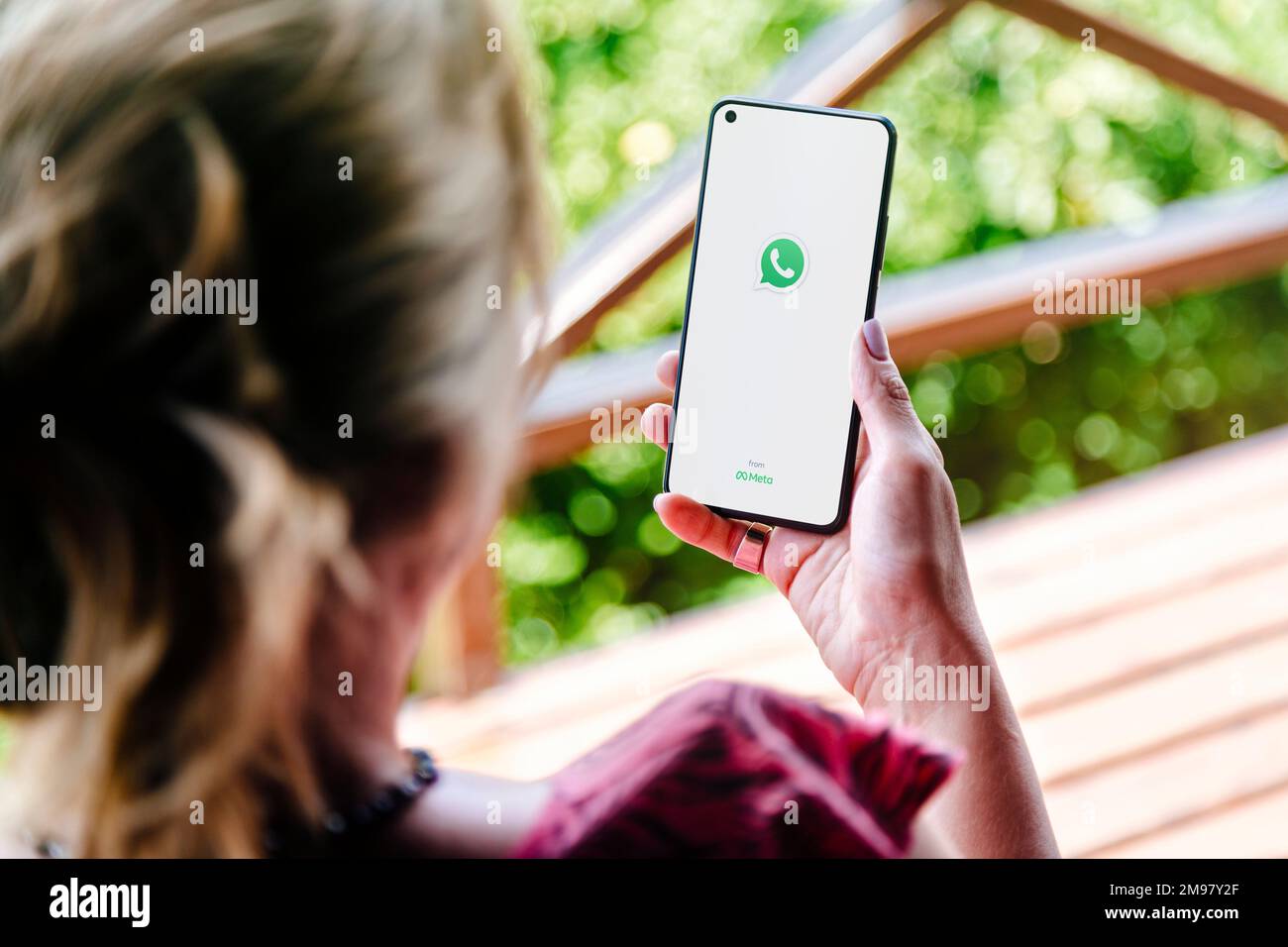 Woman with smartphone in her hands and a whatsapp intro screen ...