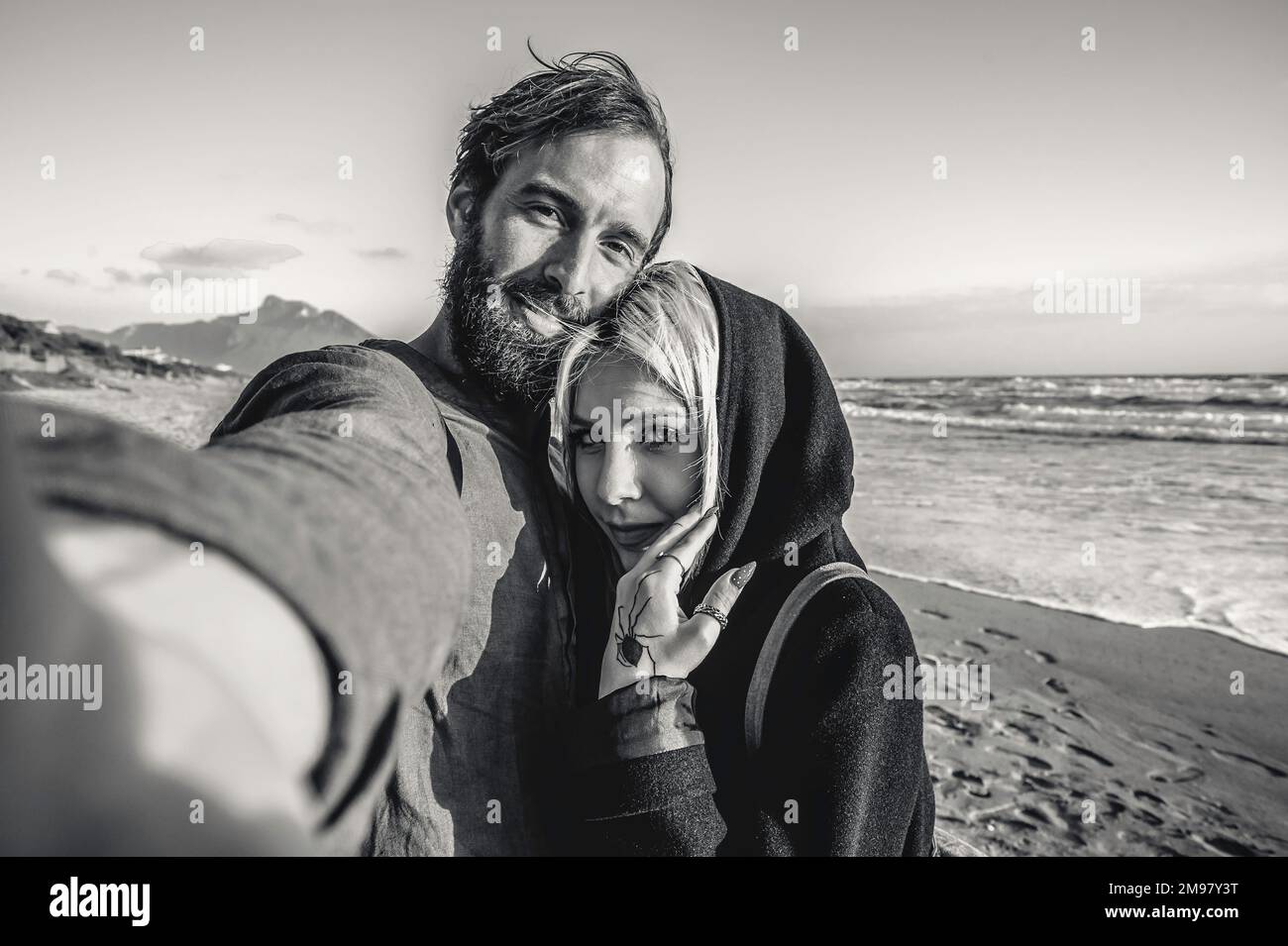 Traveling couple in love taking selfie in a deserted beach at sunset ...