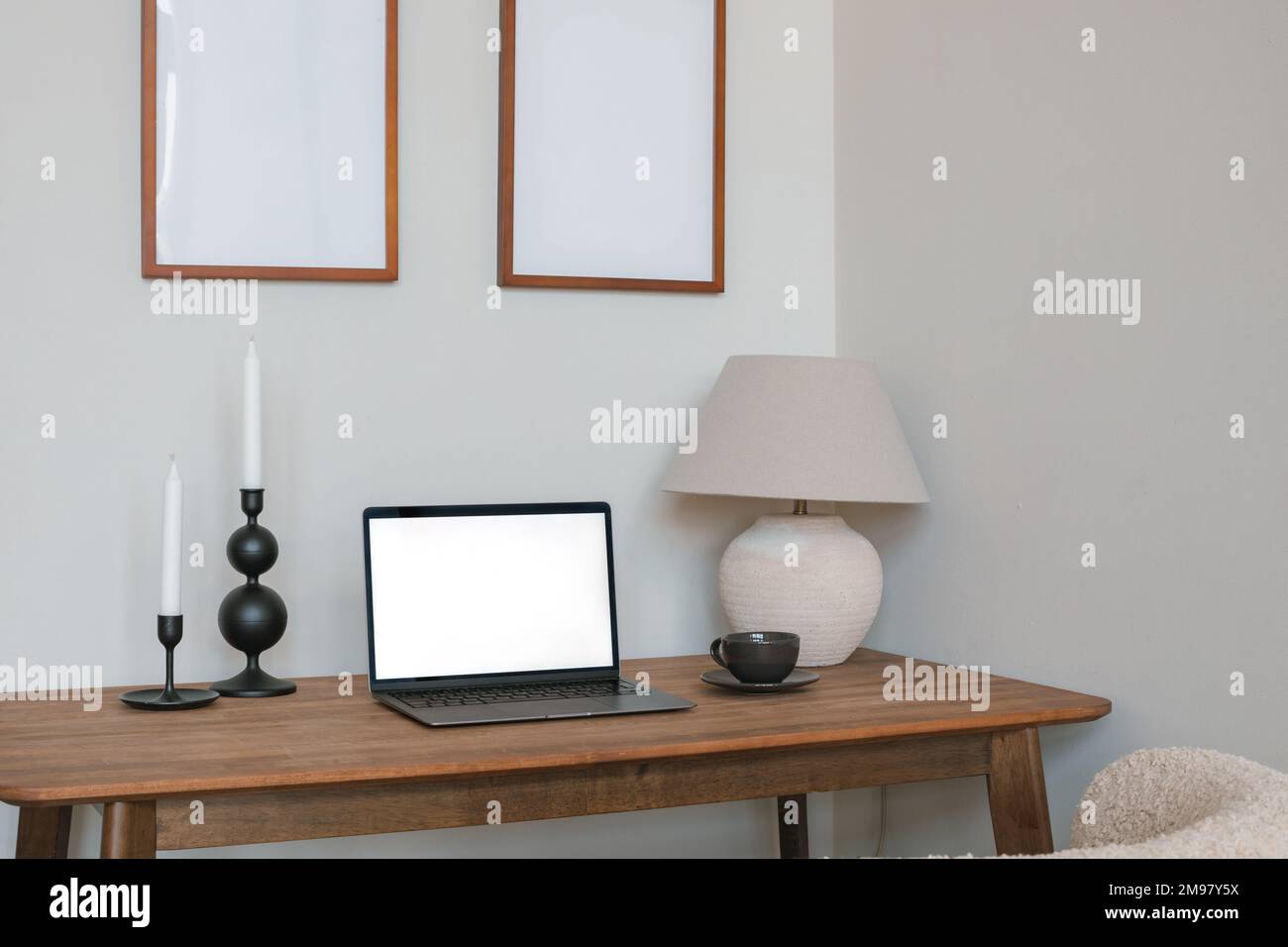 Open laptop with a blank screen, candlesticks and a lamp on a table ...
