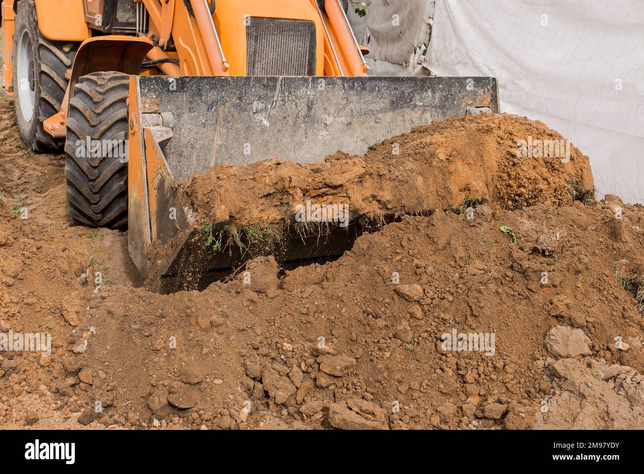 Excavator or bulldozer bucket flattens the ground or road in the ...