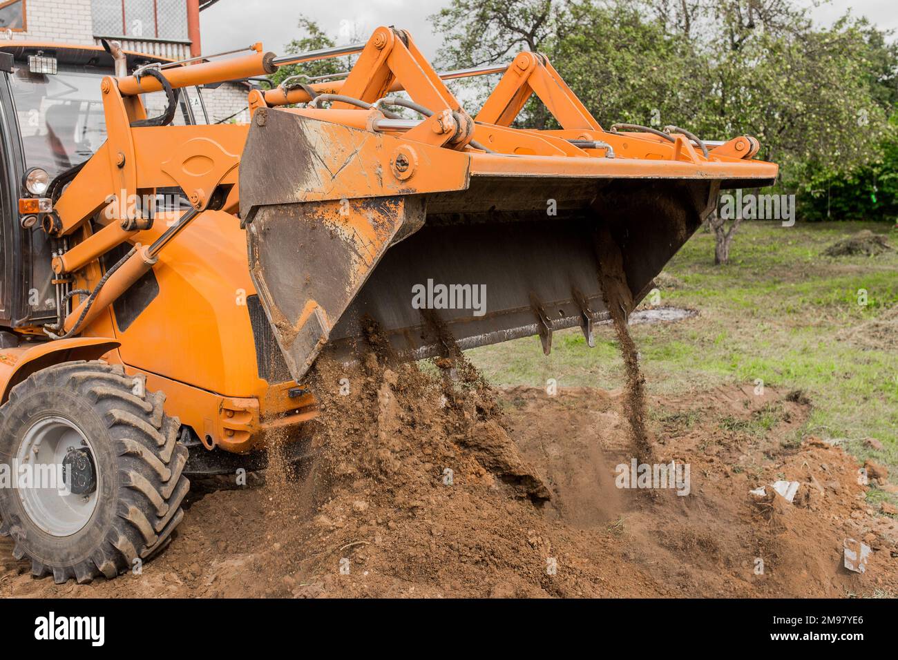 A bucket of a bulldozer fills the trench with earth in an industrial ...