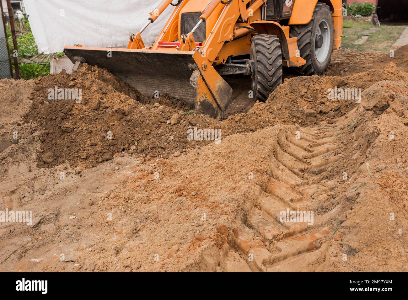 Excavator or bulldozer bucket flattens the ground or road in the ...