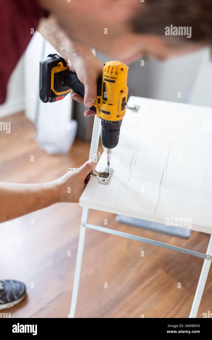 Close up man holding cordless screwdriver machine and screws lie for ...