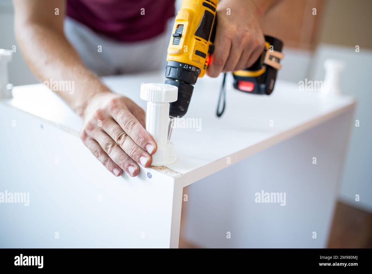 Man installing new furniture at his home and using cordless screwdriver ...