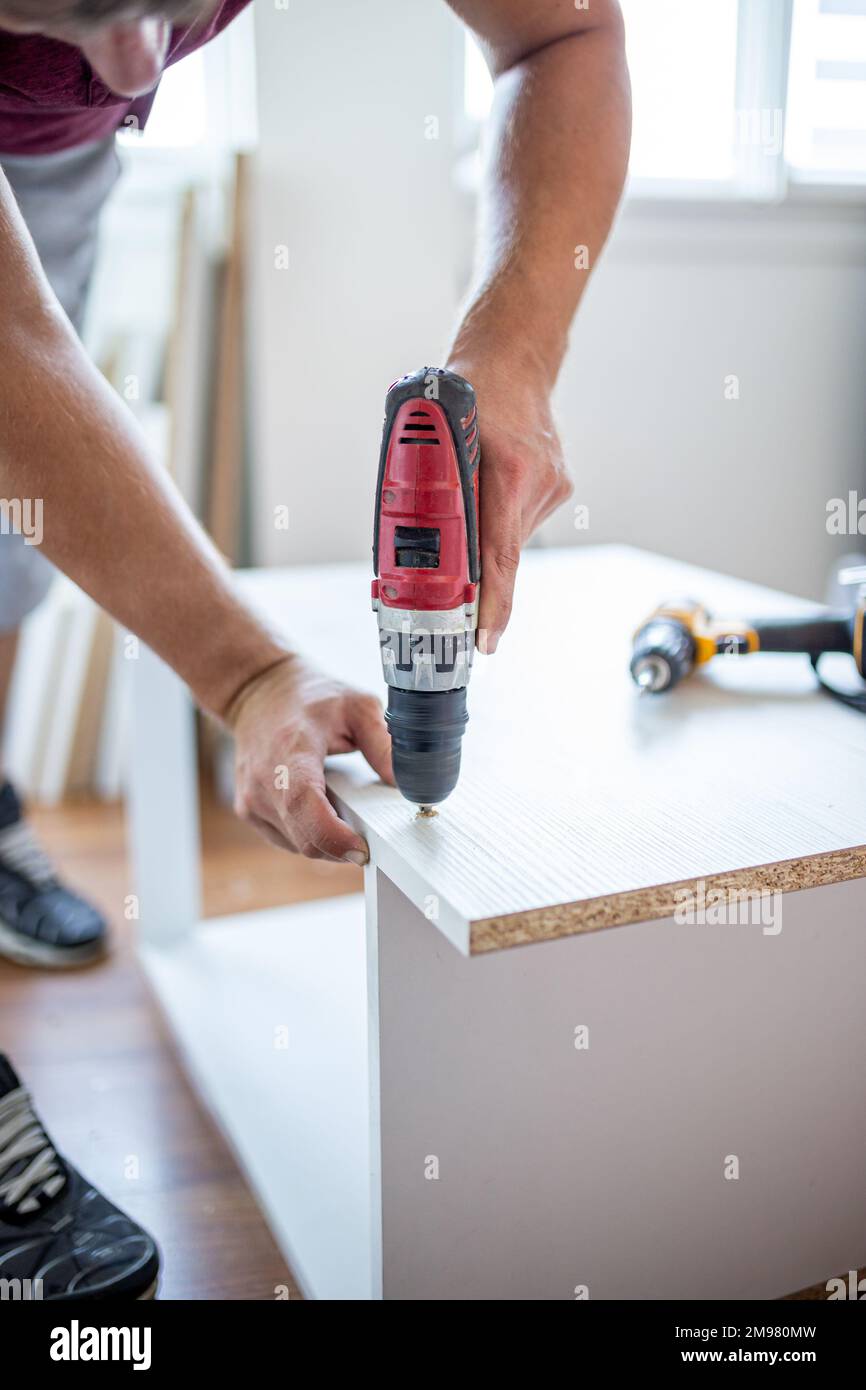 Man installing wooden shelves by using cordless screwdriver Stock Photo ...