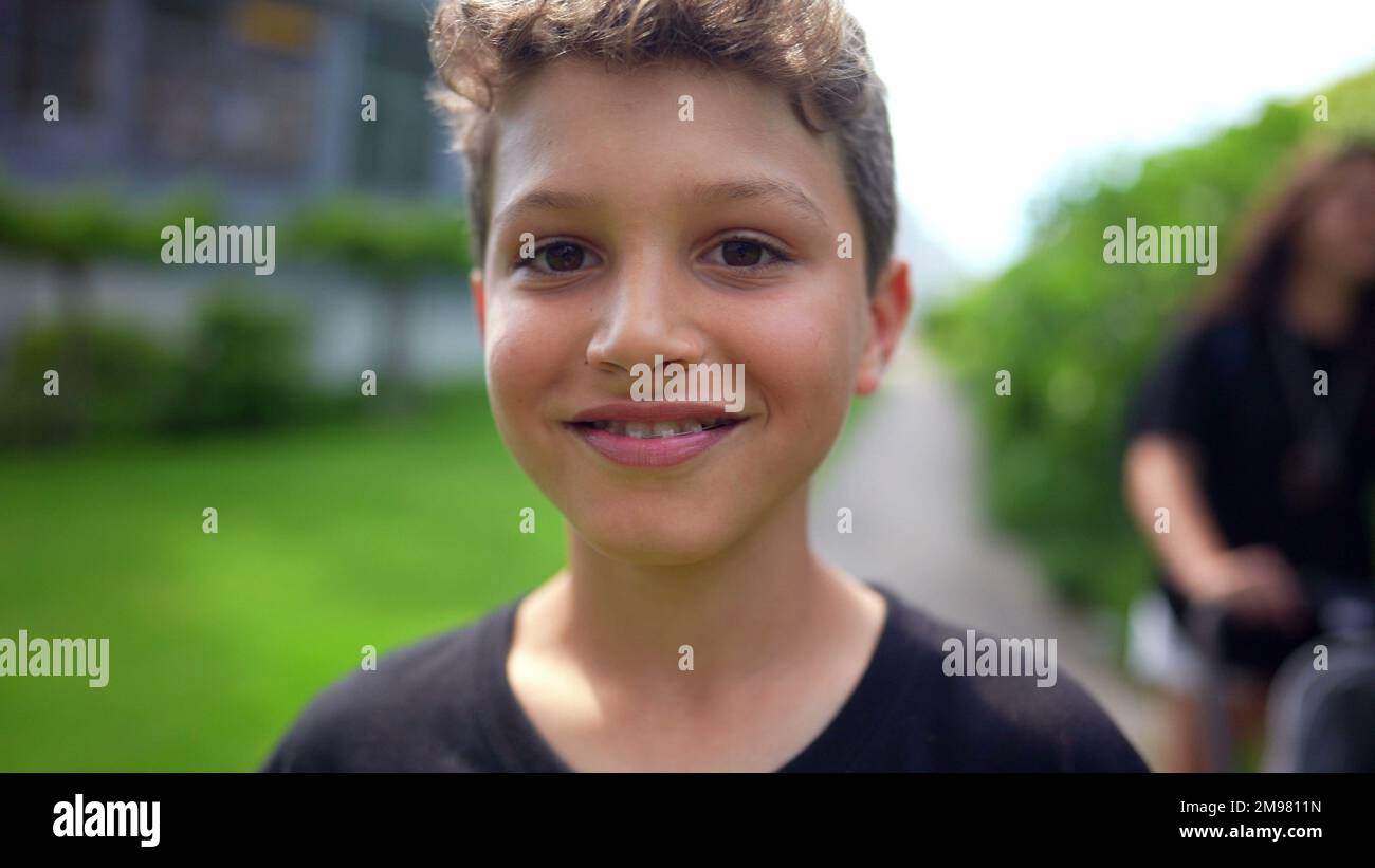 Happy little boy walking outside smiling at camera. Portrait kid close ...