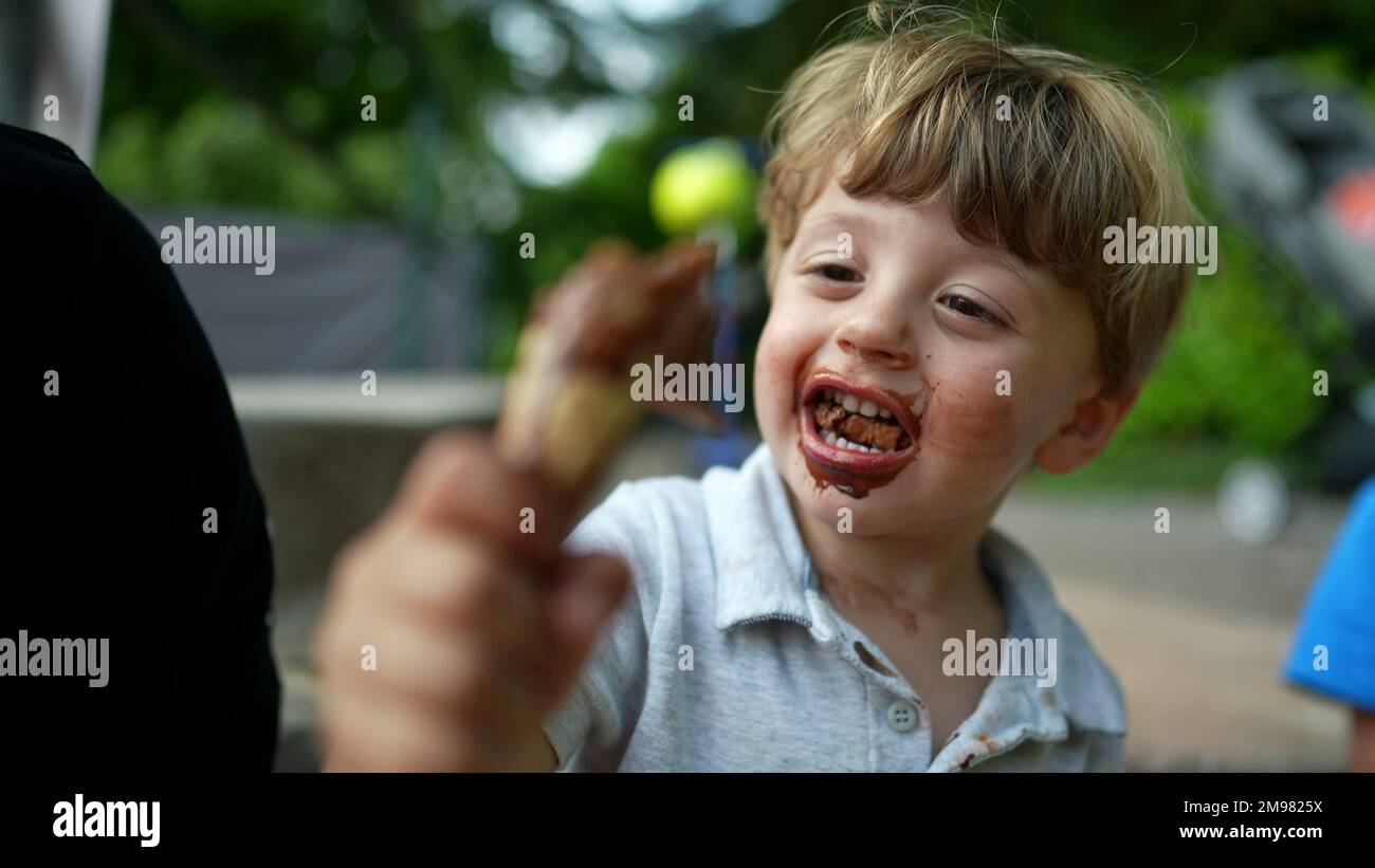 Happy toddler eating ice-cream cone. Joyful messy baby covered with ...