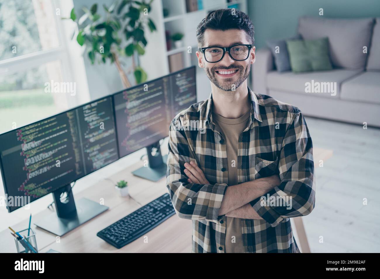 Photo of confident smiling coder dressed eyewear arms folded indoors workplace workstation loft ...