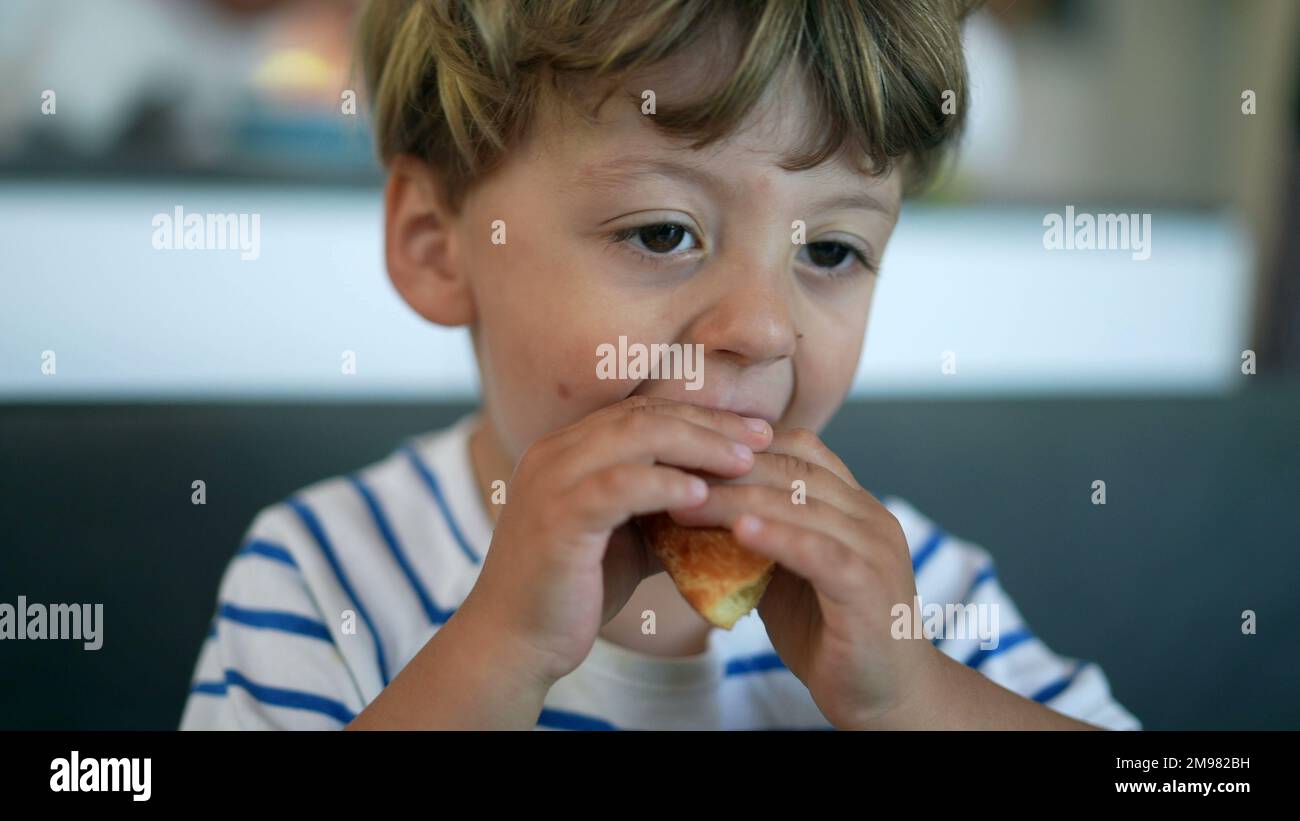 Little boy eating bread carb. Child eats piece of bread for breakfast2 ...