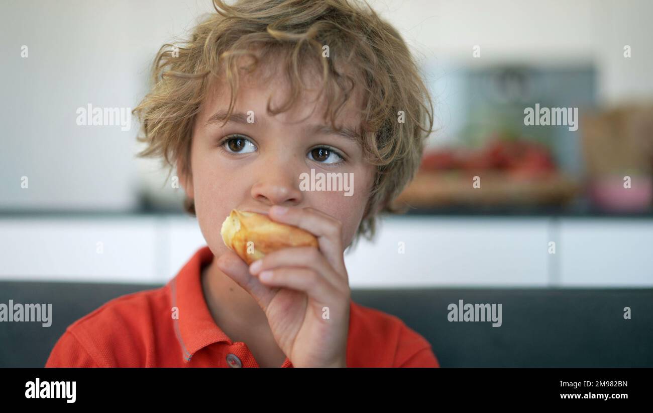 Little boy eating bread carb. Child eats piece of bread for breakfast ...
