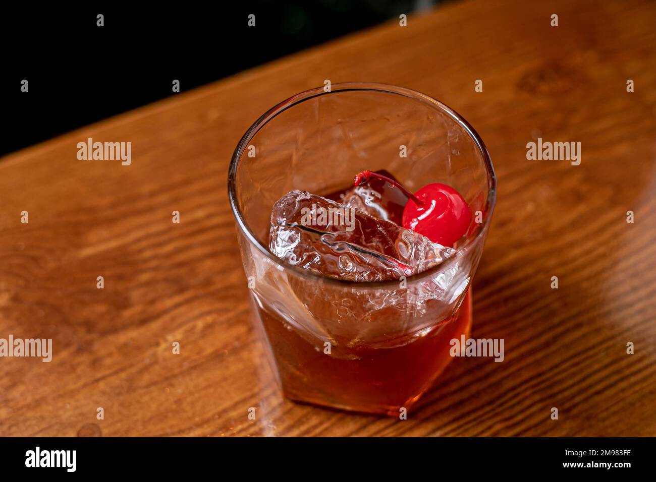 A glass of delicious sour cherry negroni cocktail on a bar counter Stock Photo - Alamy
