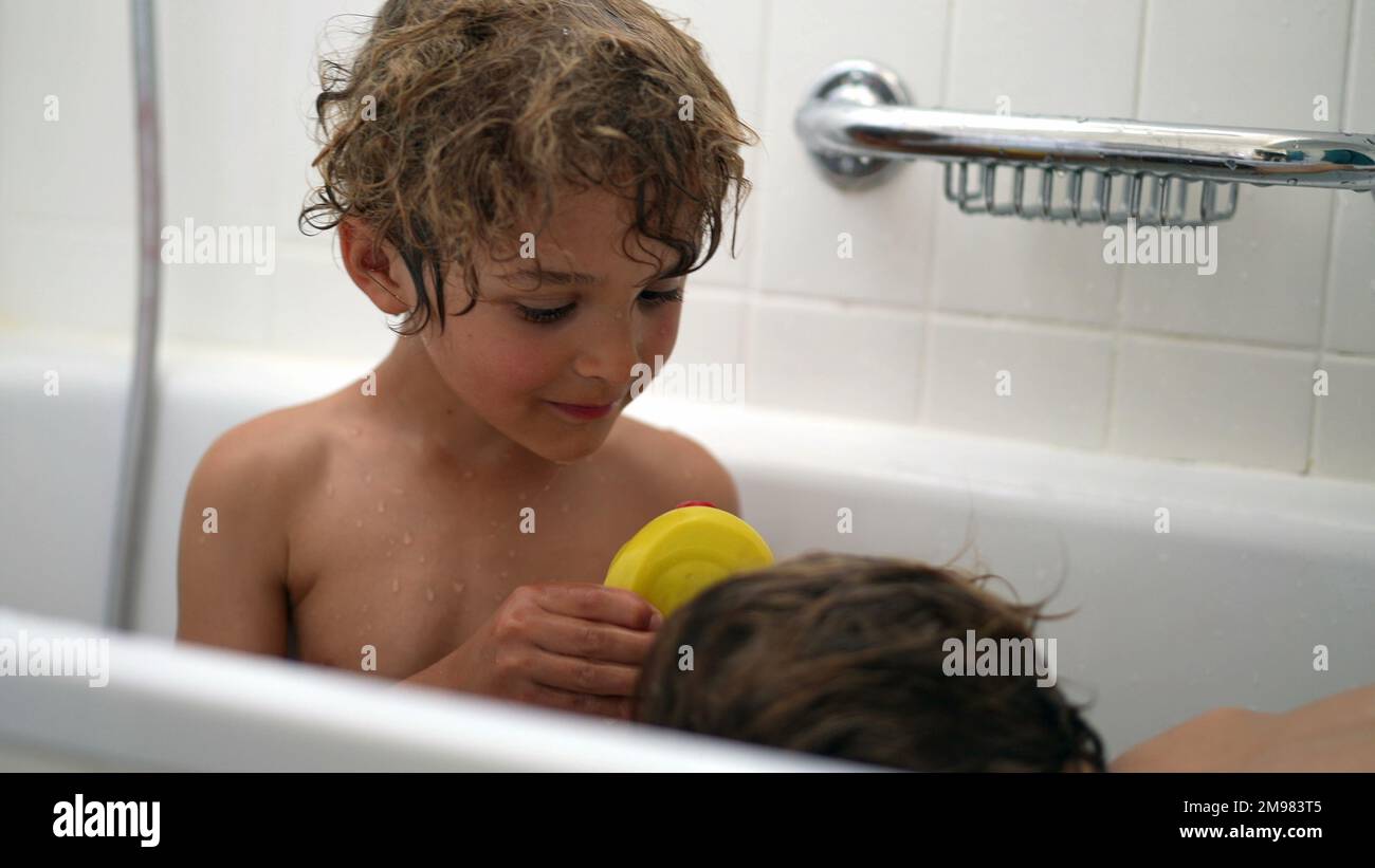 Children taking bath splashing water. Two little boys taking bath ...