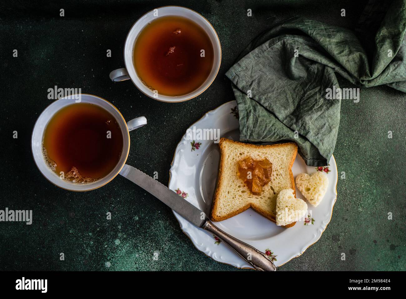 Overhead view of two cups of tea and a slice of toast with fruit jam ...