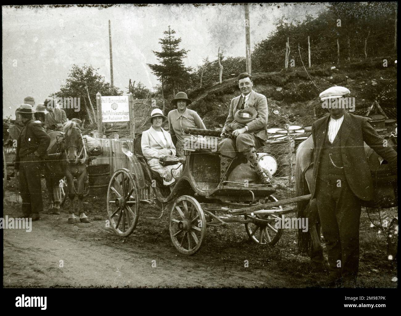 People on a trip in two horse-drawn carriages, with a Shell Petroleum ...