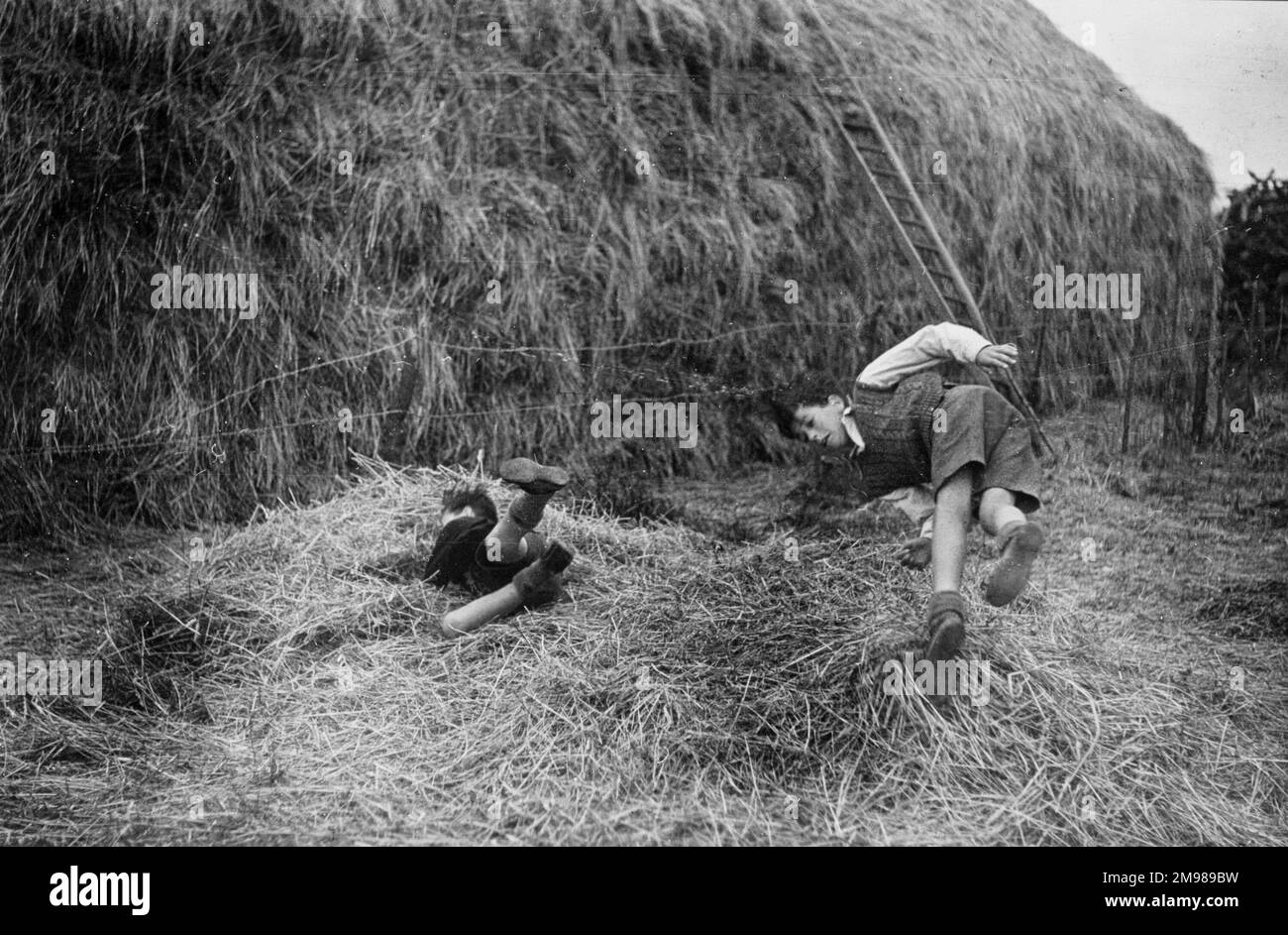 Two boys playing near a haystack Stock Photo - Alamy
