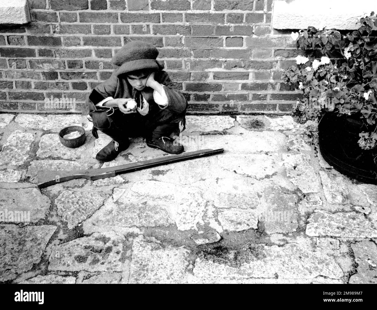 Young child in period costume eating an apple, his toy gun on the ...