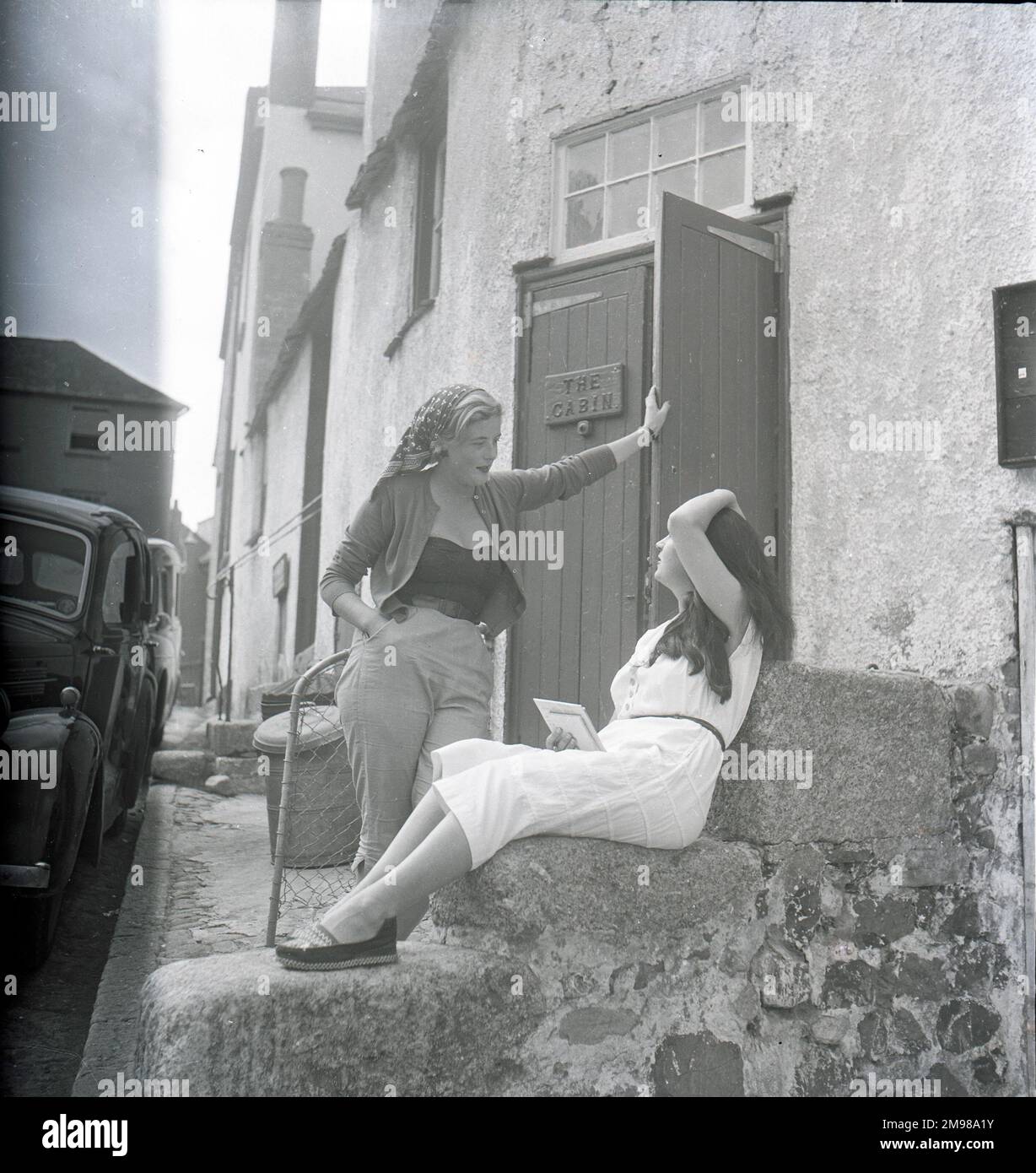 Two girls chatting on the steps of The Cabin, St Ives, Cornwall -- one ...