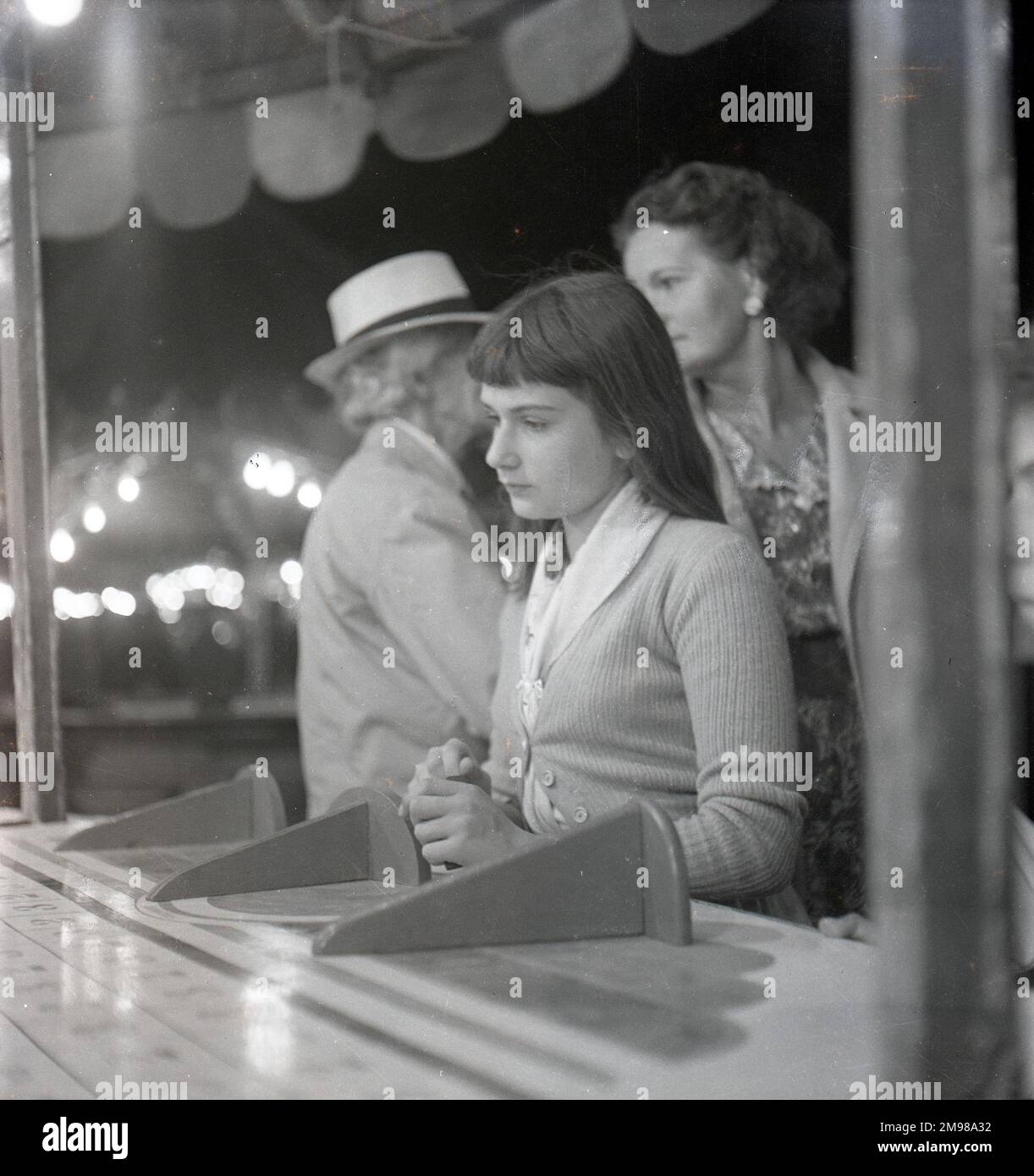 A sad-looking girl playing roll a penny, hoping to win a prize on a ...