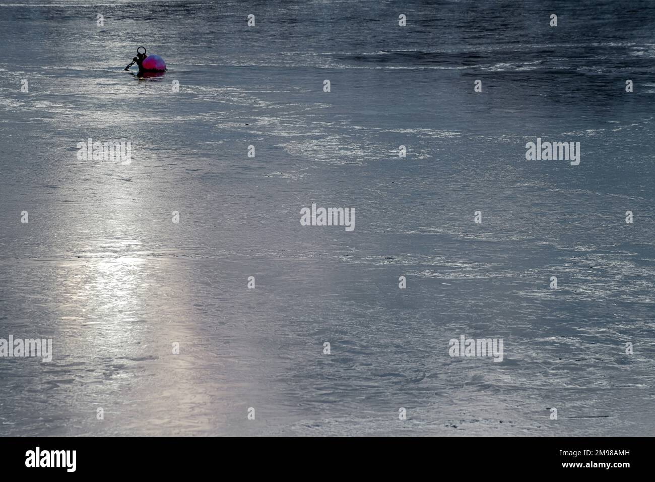 One single buoy in ice covered water. Beautiful light reflections on ...