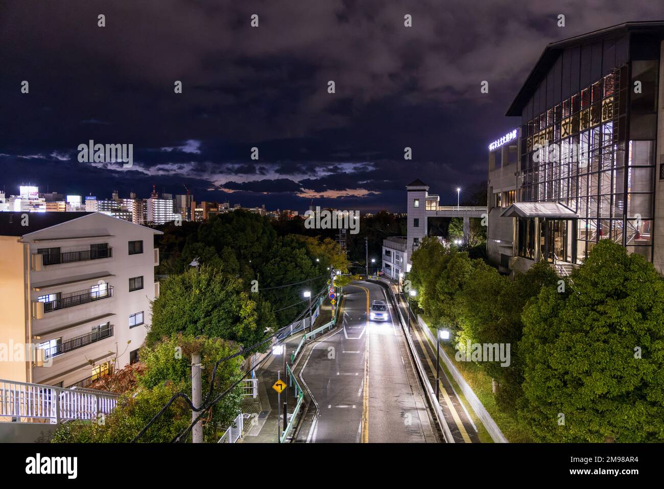 Lone car drives down quiet street under dramatic sky in early evening ...
