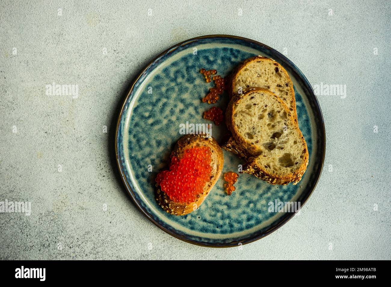 Overhead view of slices of seeded sourdough bread with red caviar on a ...