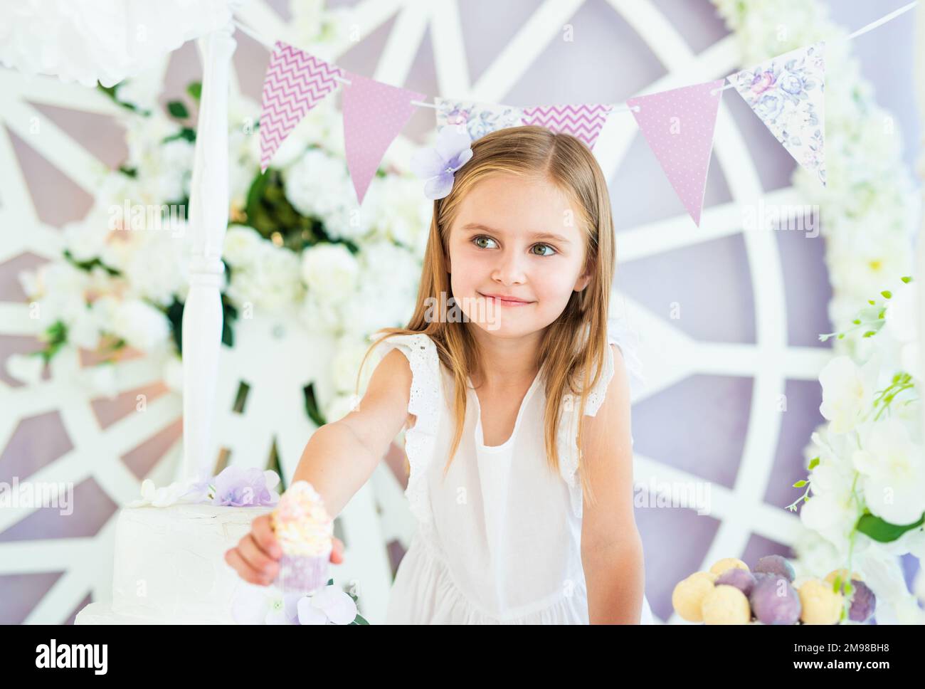 Pretty little blond girl standing in the beautiful decorated candy bar ...