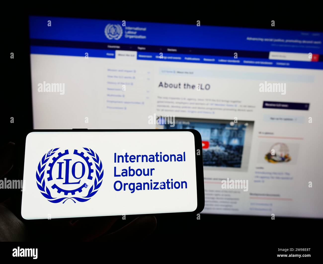 Person holding mobile phone with logo of UN agency International Labour ...