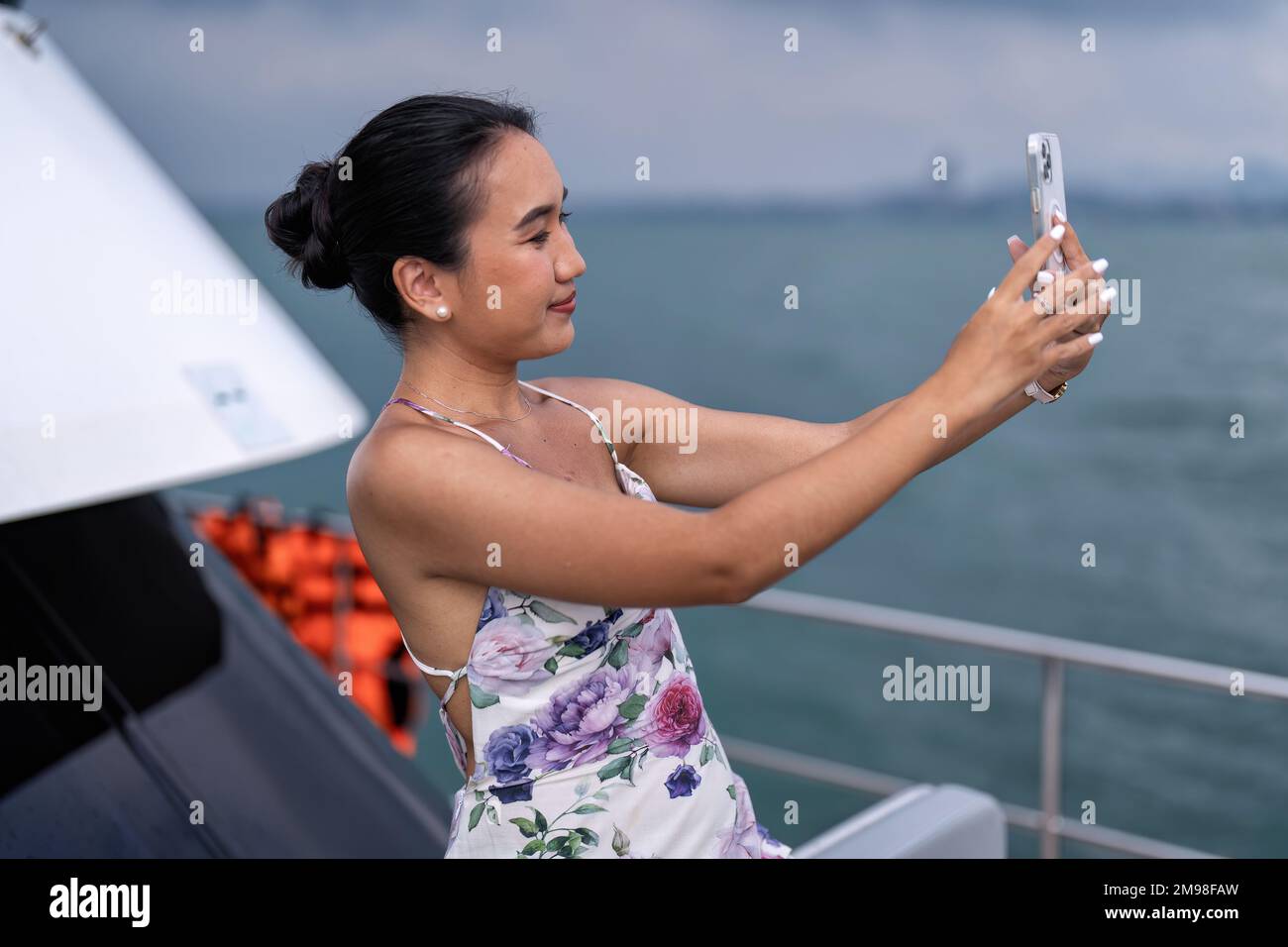 Beautiful girl have fun sailing in the sea sitting on yacht deck enjoy amazing view and selfie ...
