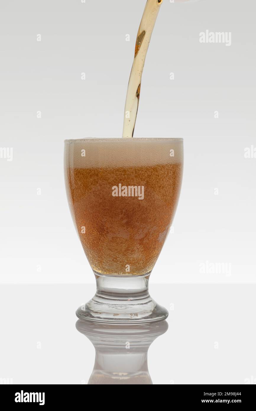 vertical photo of a stream of beer falling into a glass on a white ...