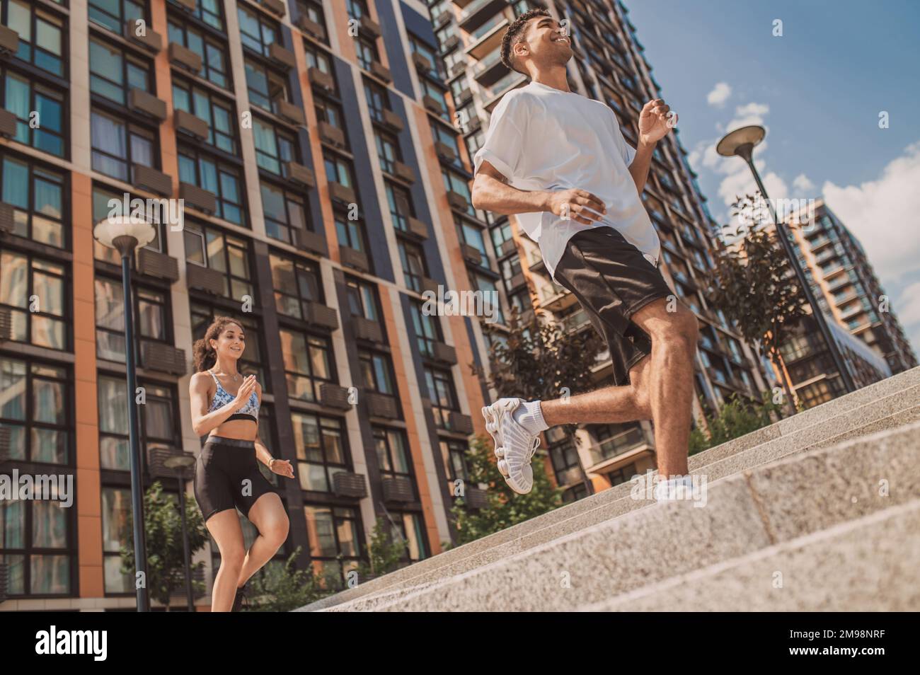 Athletic guy and a fit girl running together outdoors Stock Photo - Alamy