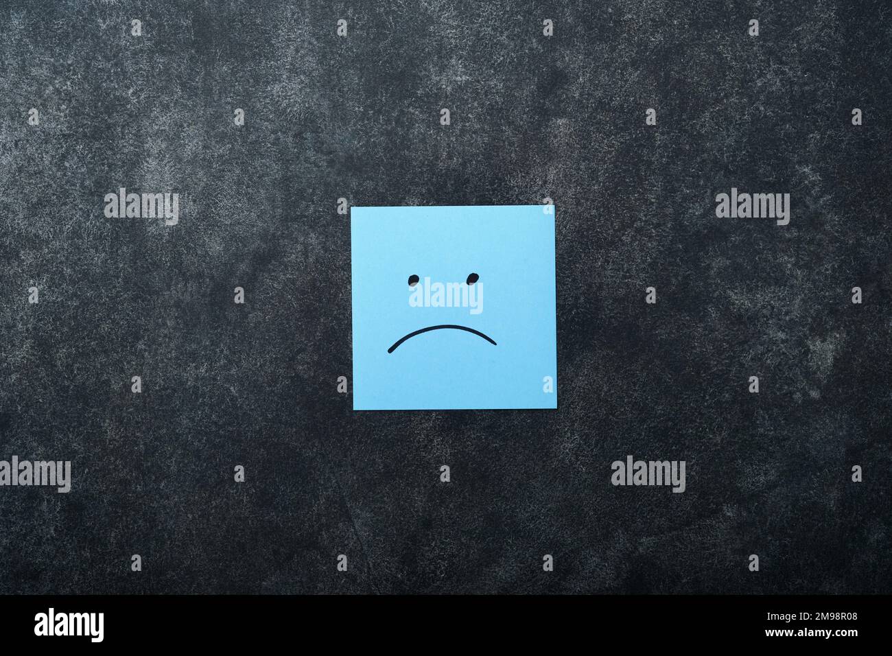 Blue sticky notes blank with drawing sad face on black background with ...