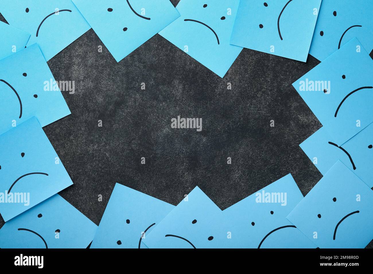 Blue sticky notes blank with drawing sad face on black background with ...