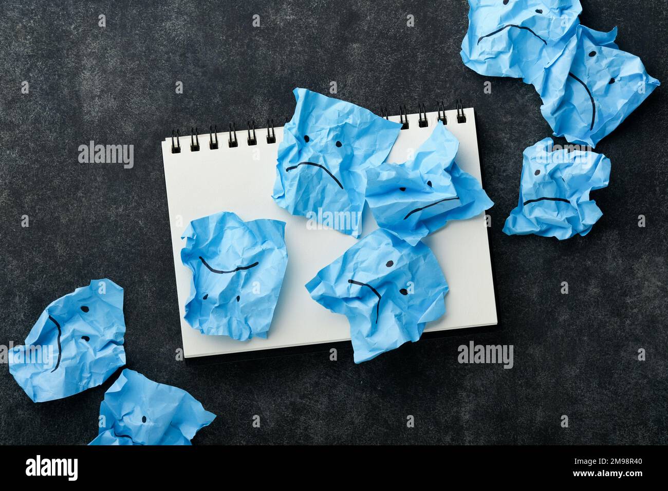 Blue crumpled sticky notes blank with drawing sad face on black ...
