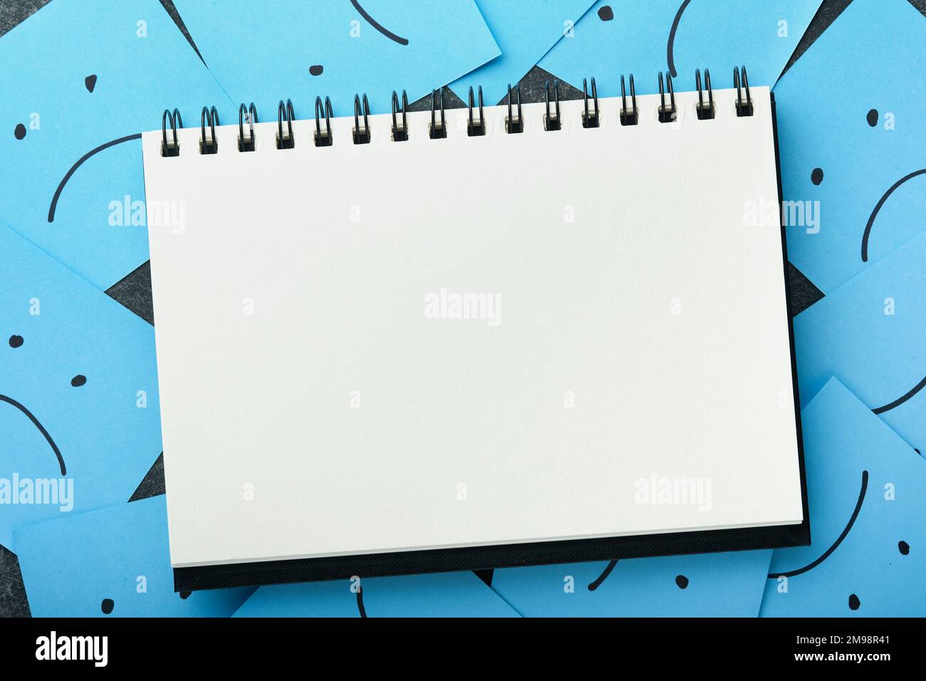 Blue sticky notes blank with drawing sad face on black background with ...