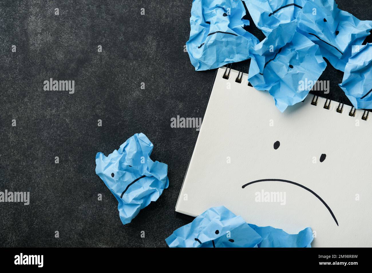 Blue crumpled sticky notes blank with drawing sad face on black ...