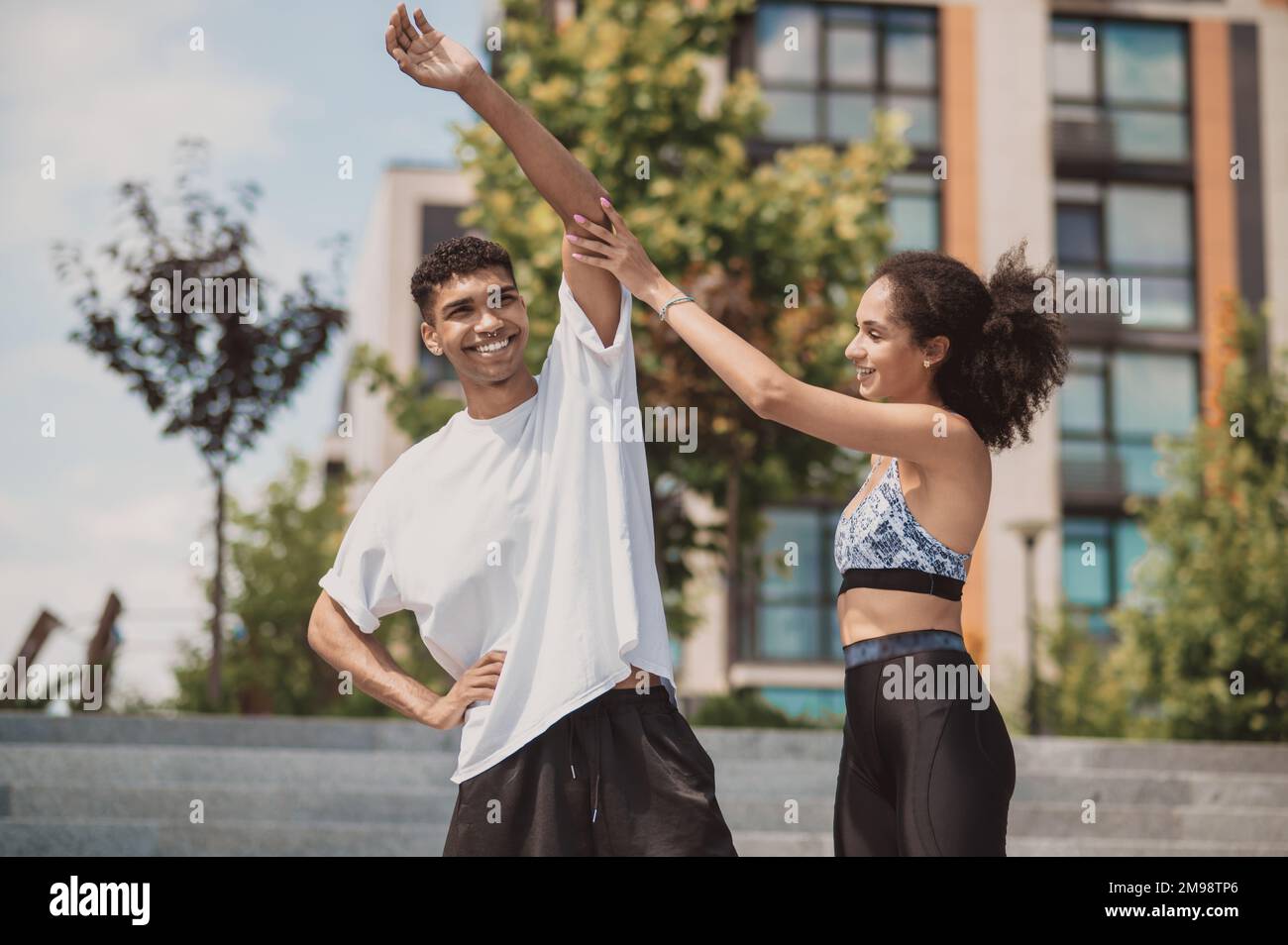 Guy doing a stretching exercise supervised by his personal trainer ...
