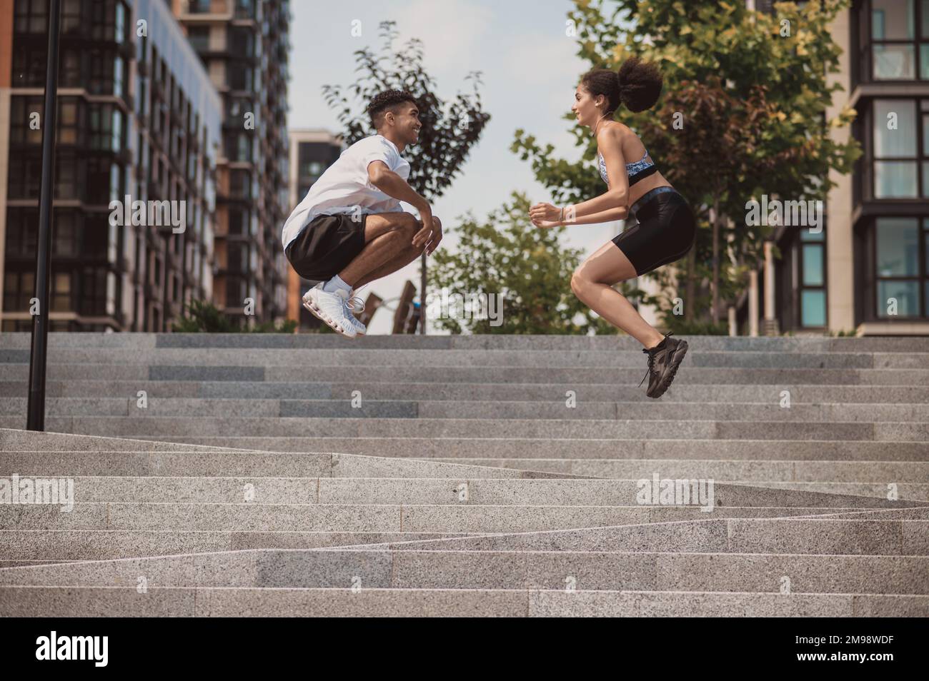 Cheerful couple of athletes doing the high jumps Stock Photo - Alamy