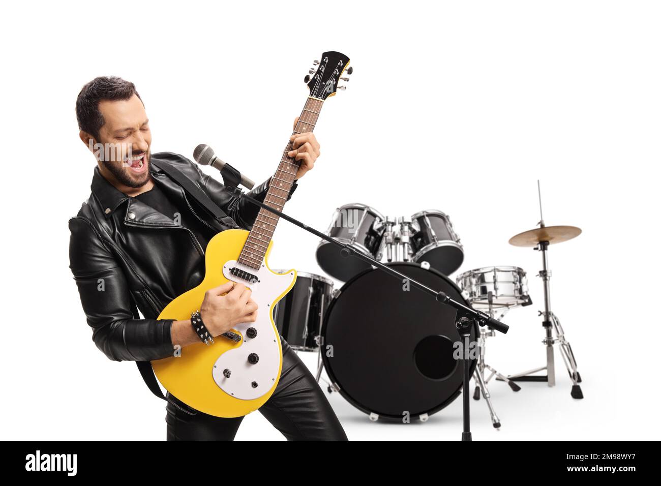 Rocker guitarist playing an electric guitar in front of a drum set ...