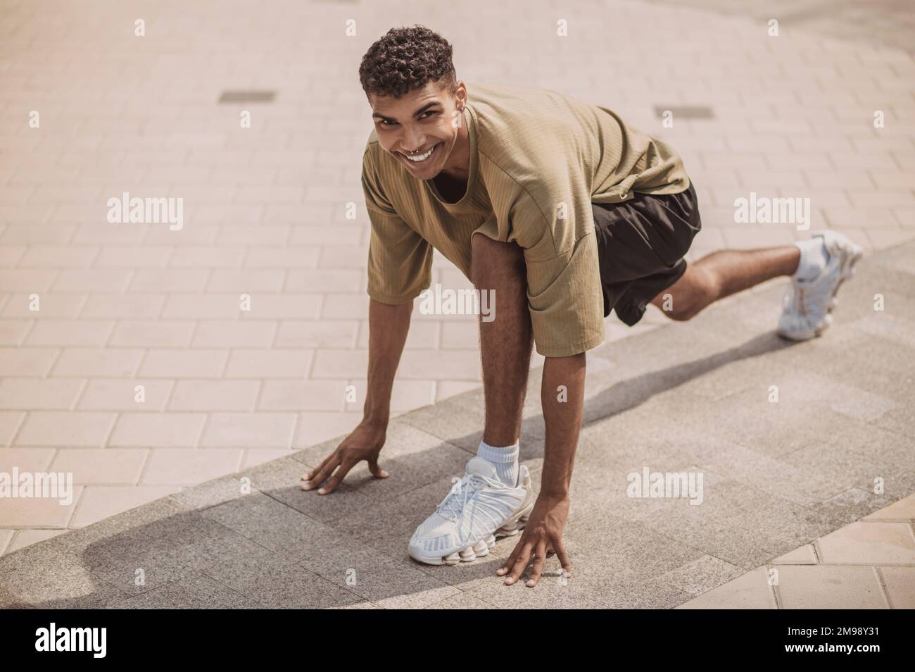 Cheerful athlete stretching his leg muscles during the outdoor workout ...