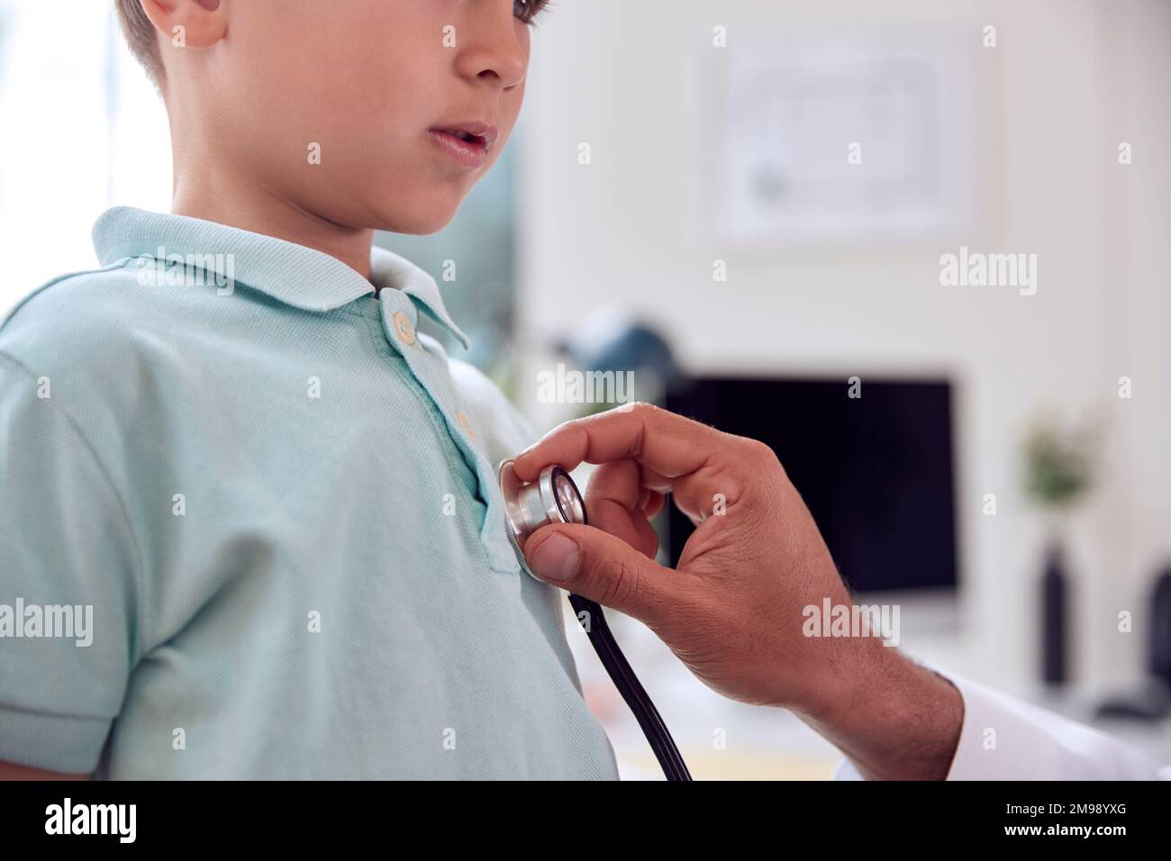 Close Up Of Male Doctor Or GP Wearing White Coat Examining Boy ...