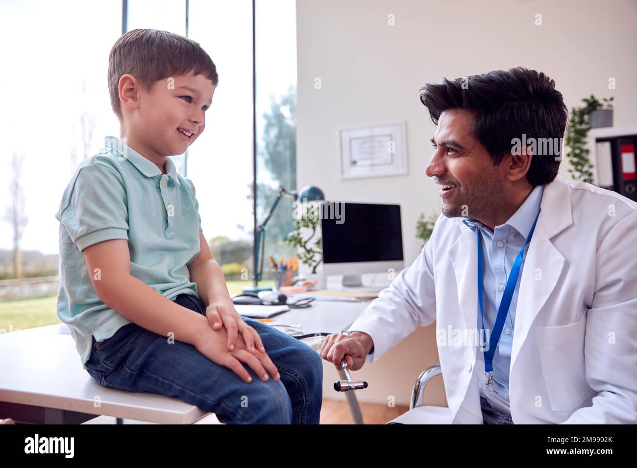 Male Doctor Or GP Wearing White Coat Examining Smiling Boy Testing ...