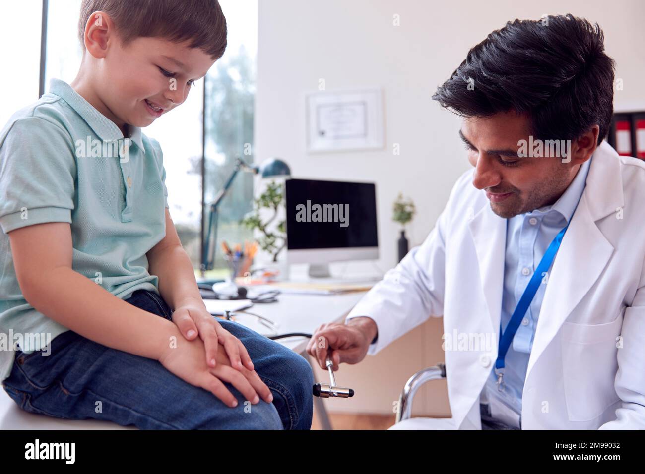 Male Doctor Or GP Wearing White Coat Examining Smiling Boy Testing ...
