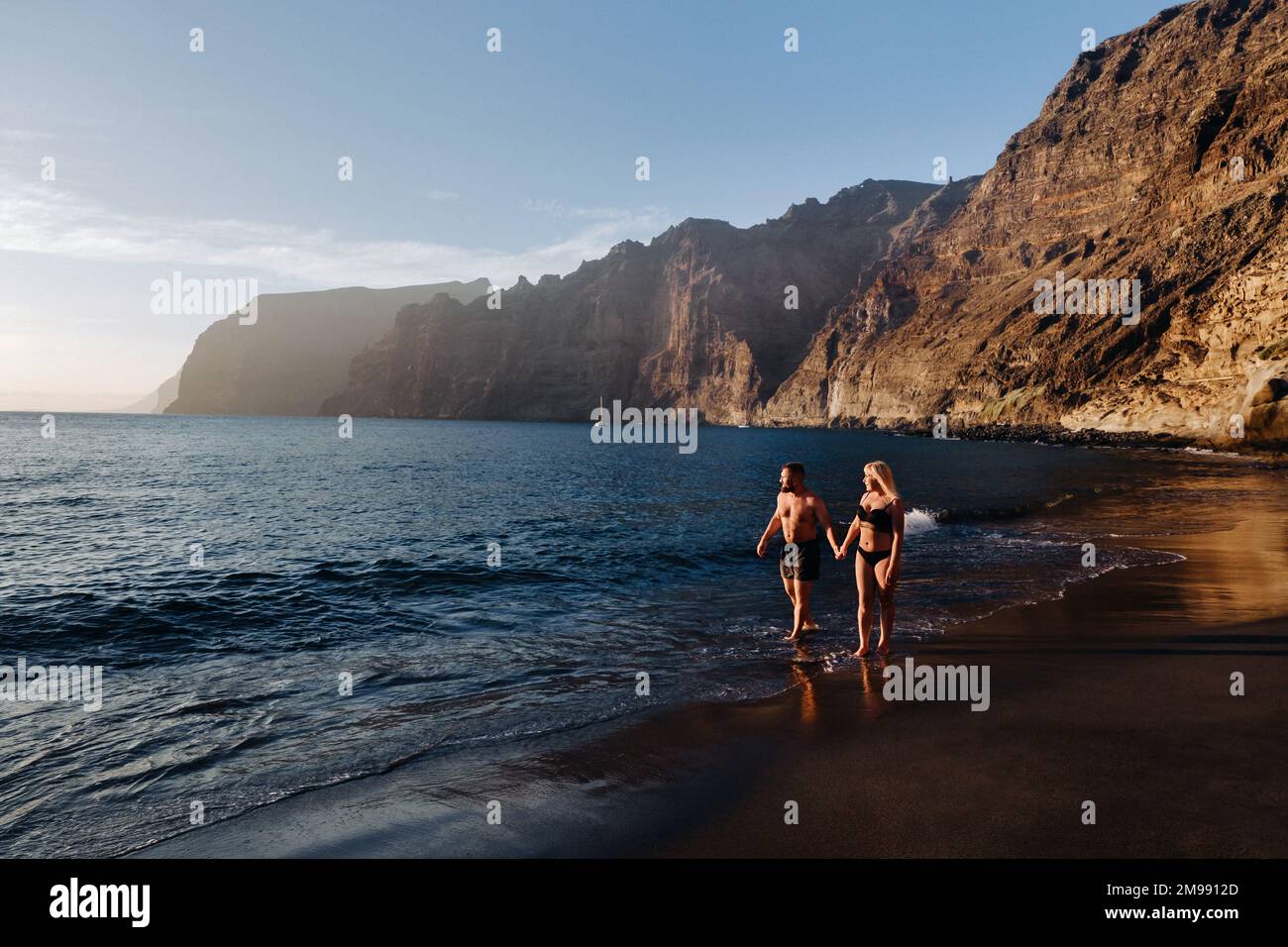 A couple in love walks on the beach against the backdrop of the ...