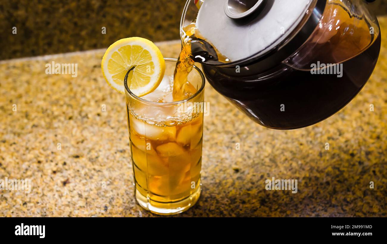 Pouring fresh brewed iced tea into clear glass. Pitcher of tea pouring ...