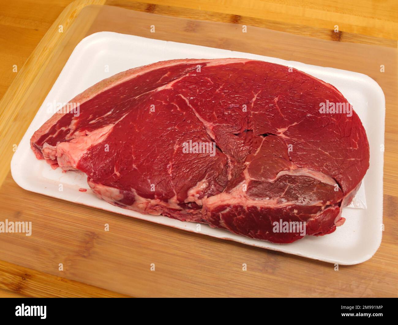 Raw uncooked meat. Sirloin steak in a butcher tray on a wooden cutting ...