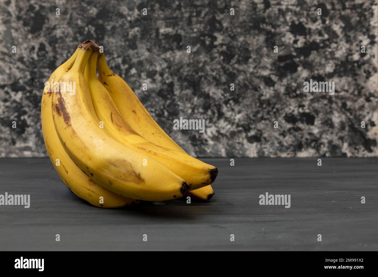 Group of bananas on a gray table and copy space Stock Photo - Alamy