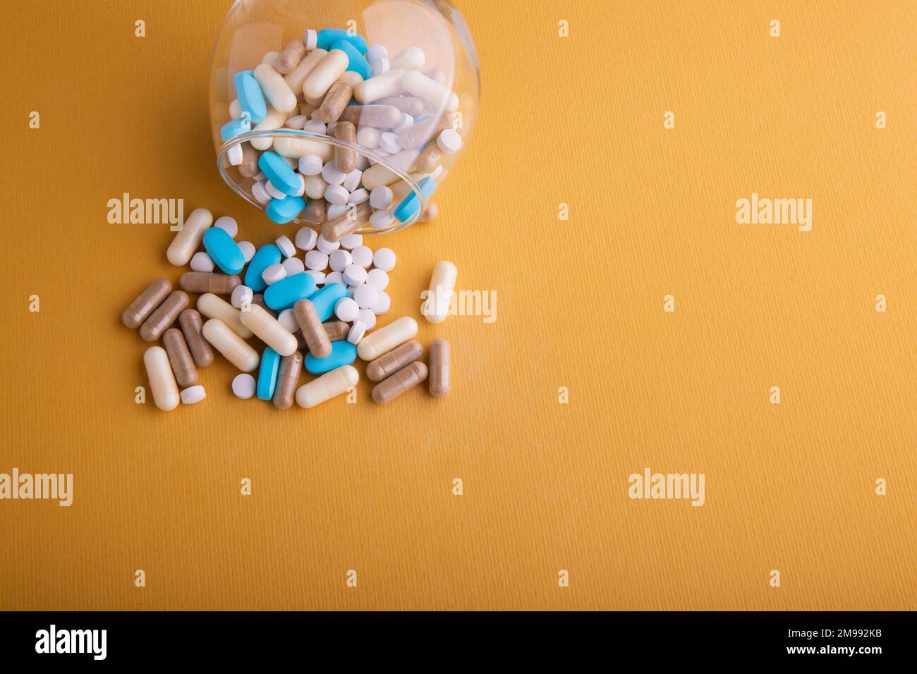 A high-angle shot of blue, white, and brown oval medicine in the glass ...